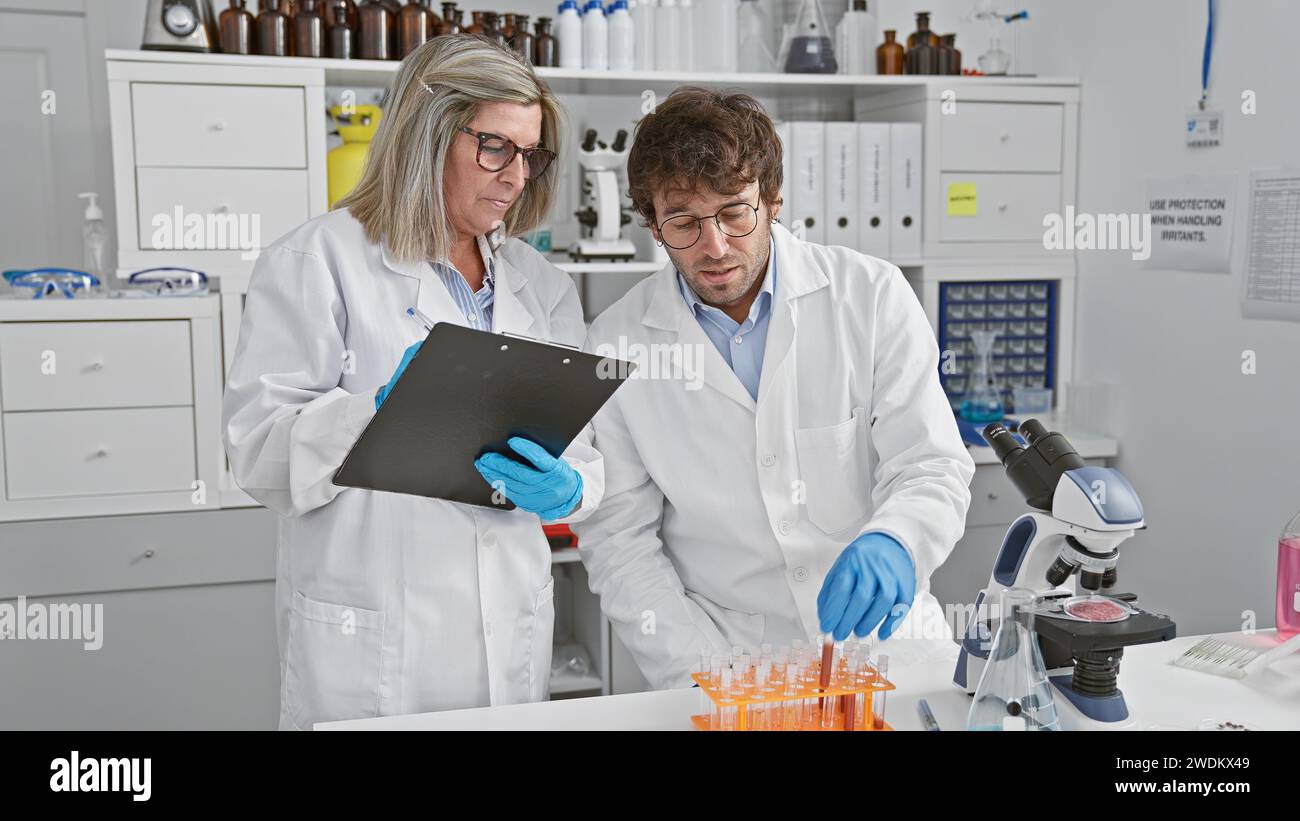 Inside the lab, two professional scientists - a man and woman, united ...