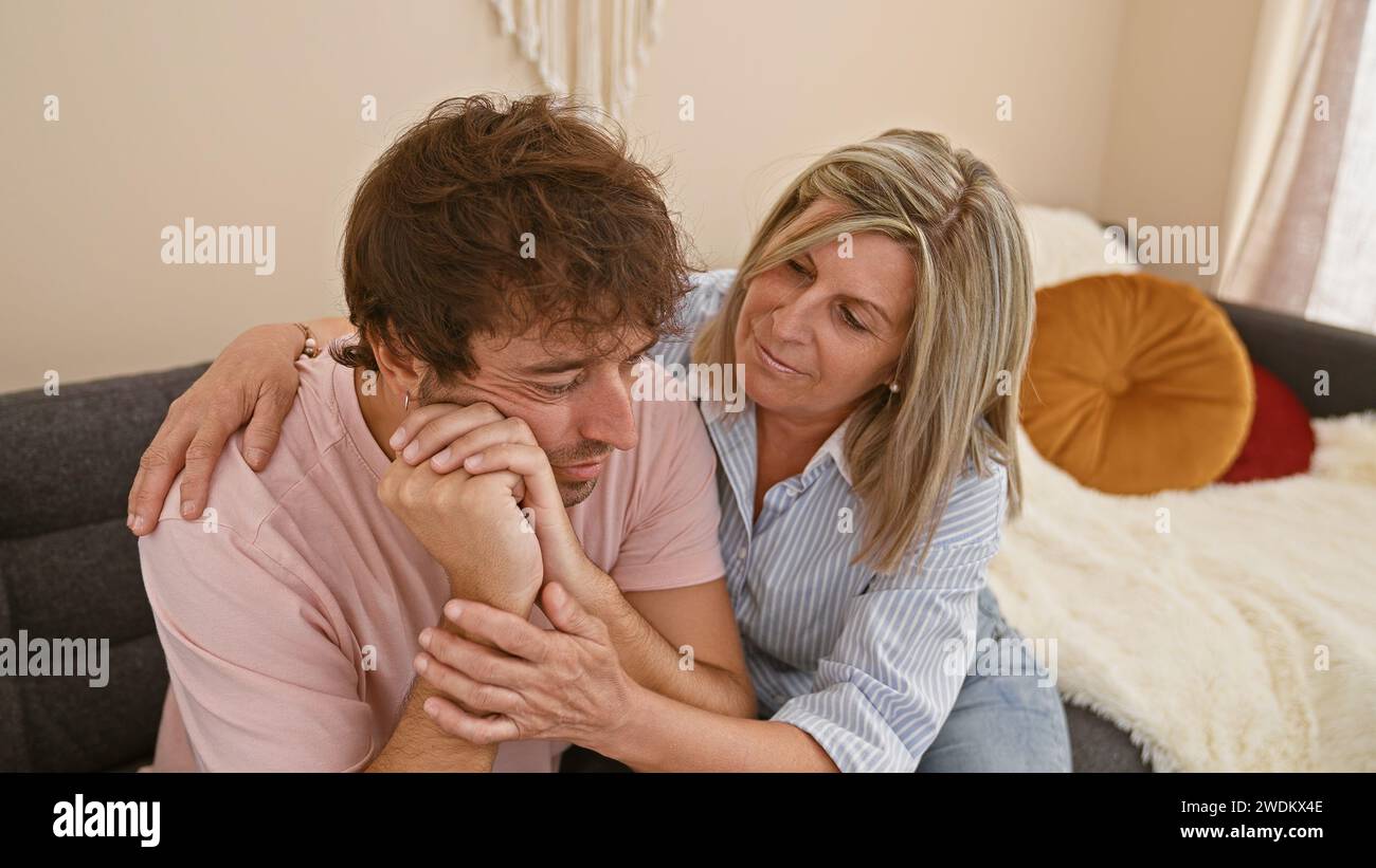 Mother and son share supportive hug, sitting on sofa at home, family ...
