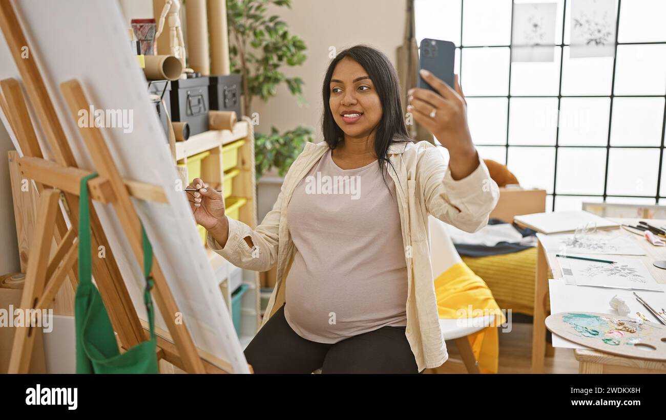 Expecting young latina artist, joyfully smiling as she draws her ...