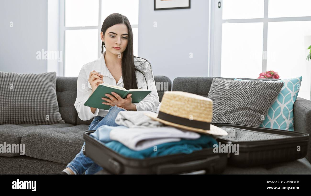 A thoughtful young woman sits at home writing in a notebook, with a ...