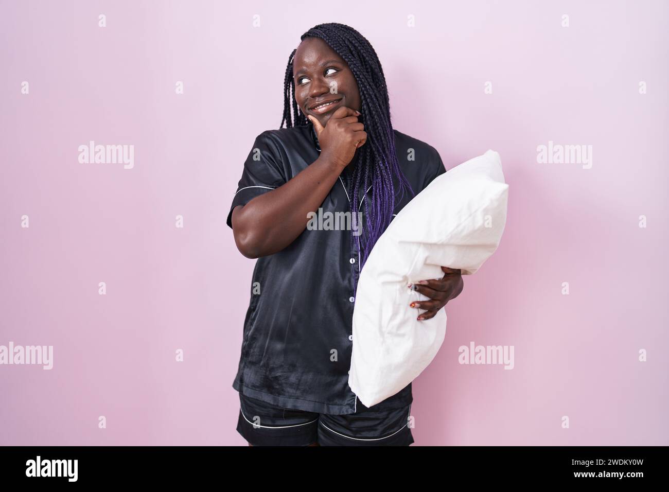 Young african woman wearing pijama hugging pillow looking confident at ...