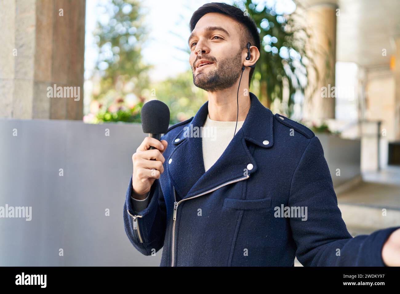 Young hispanic man reporter working using microphone at street Stock Photo - Alamy