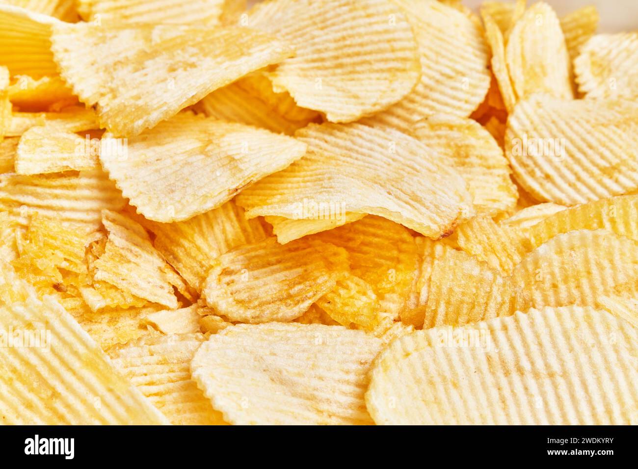 Close-up view of crispy, golden potato chips filling the frame, evoking ...