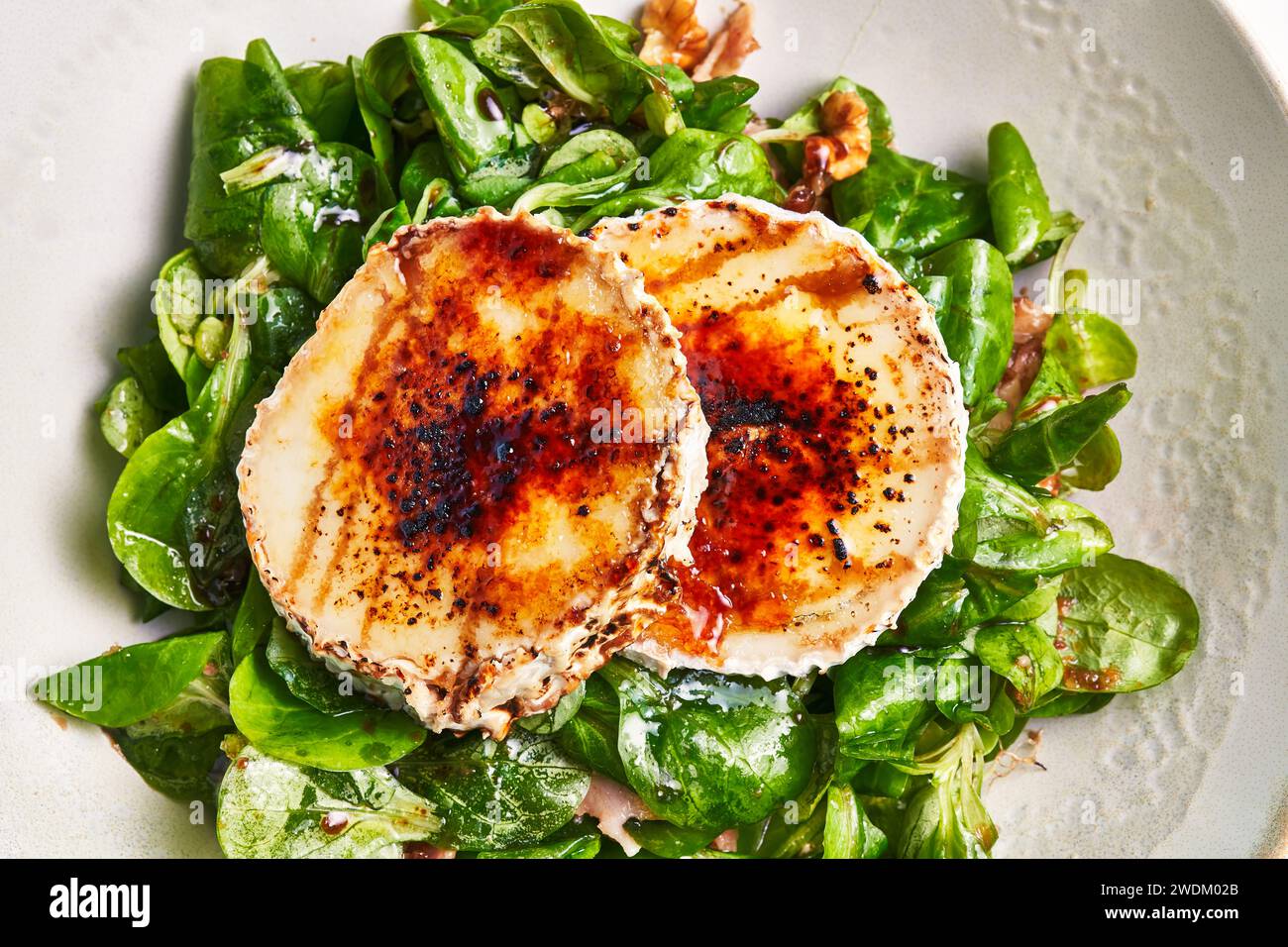 A gourmet dish featuring caramelized goat cheese atop a fresh spinach ...
