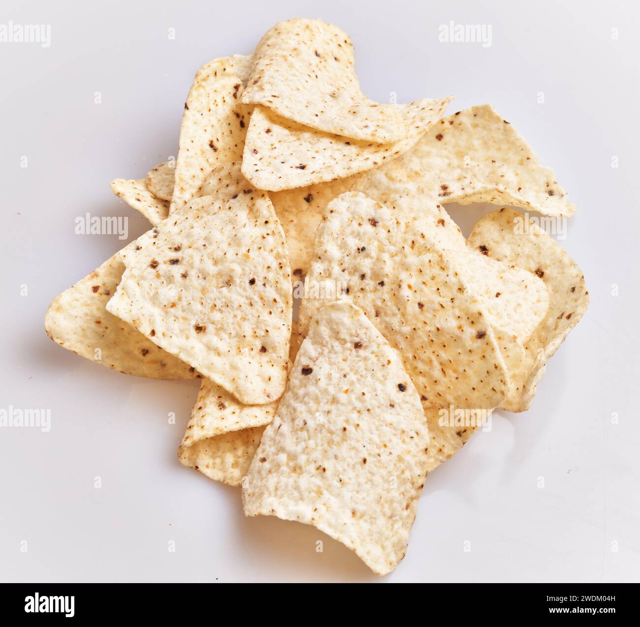 Close-up of a fresh pile of tortilla chips on a plain white background ...