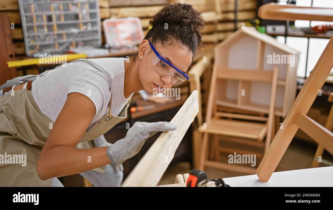 Beautiful young hispanic female carpenter gently touching a plank of ...