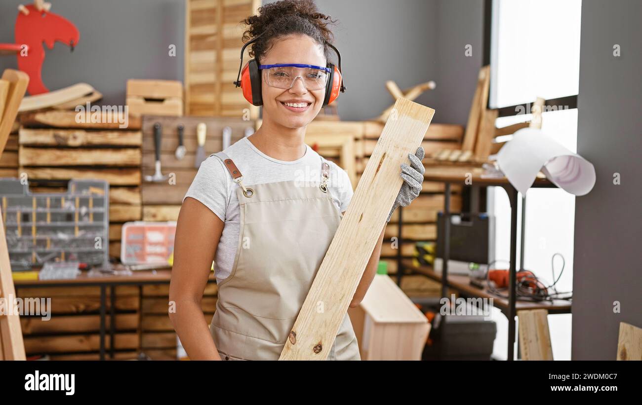 Smiling young hispanic woman, a beautiful carpenter in glasses, happily ...