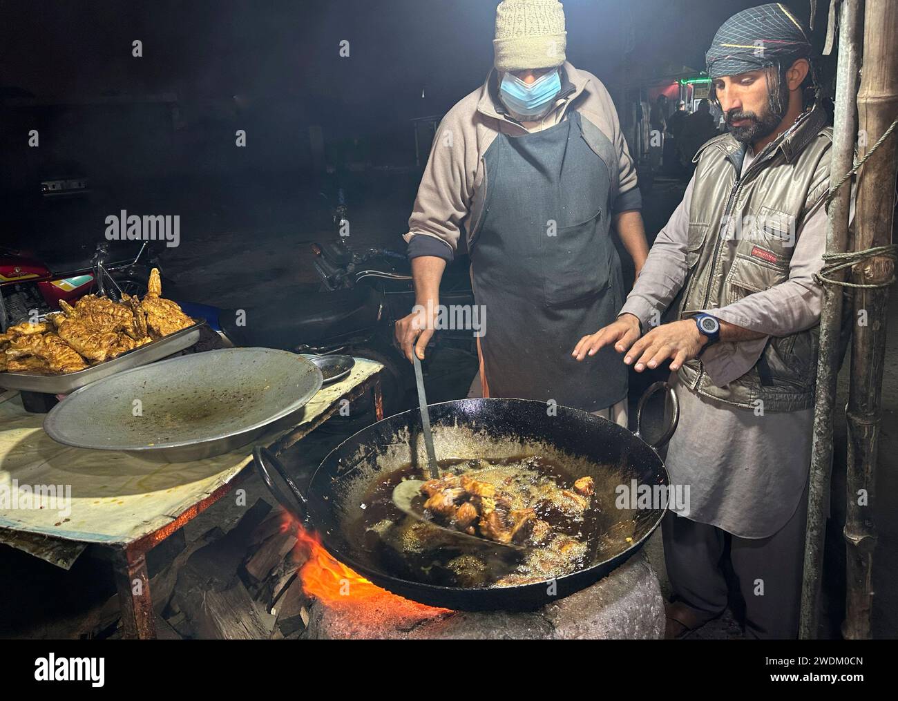 A Pakistani man, left, cooks at street stall in Islamabad, Pakistan ...
