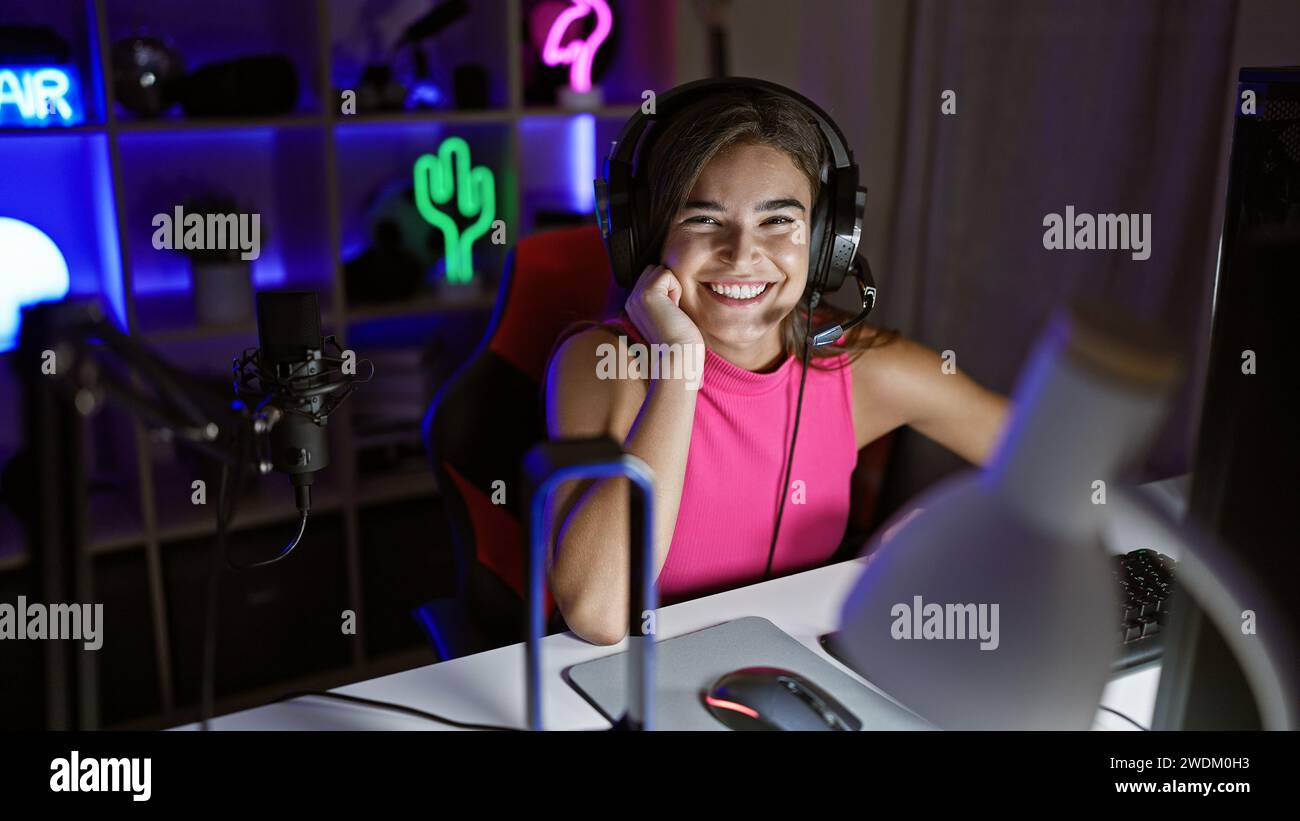 Smiling beautiful young hispanic woman streamer playing video game ...