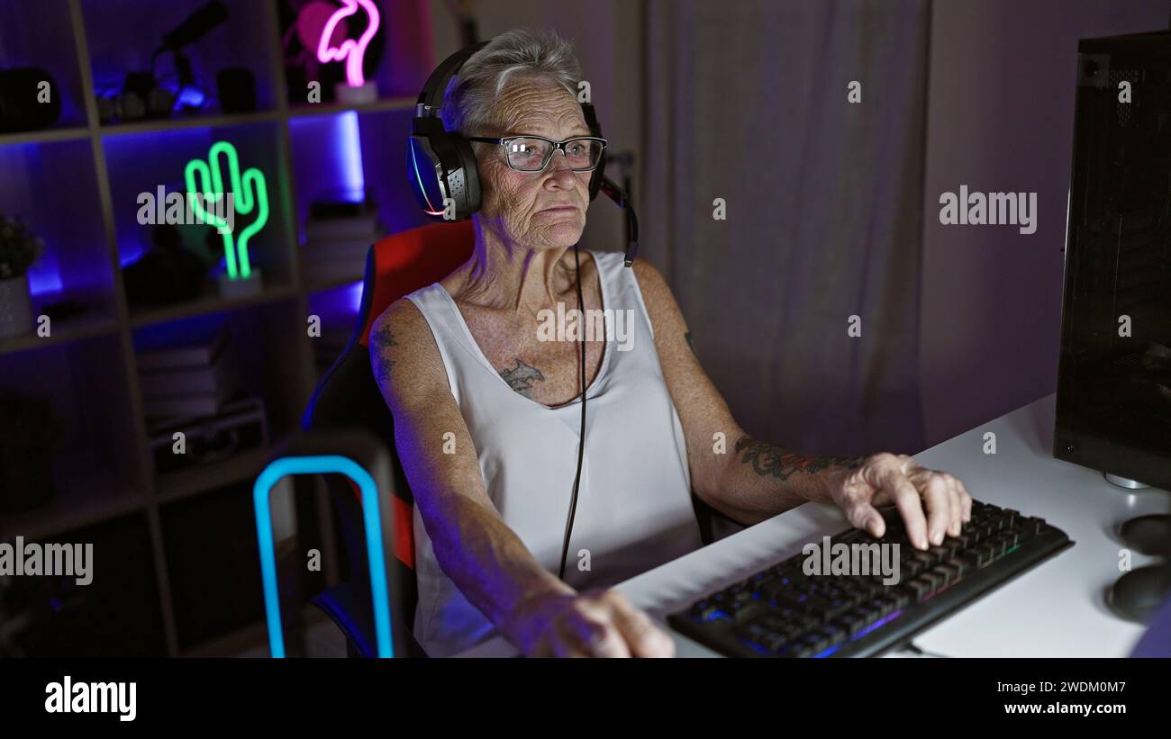 Serious grey-haired senior woman streamer engrossed in a nighttime ...
