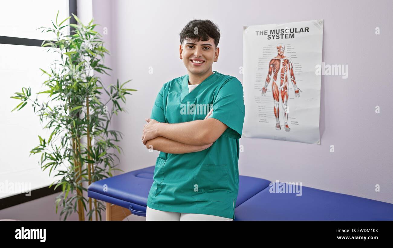 Confident young man in scrubs standing with arms crossed in a medical ...