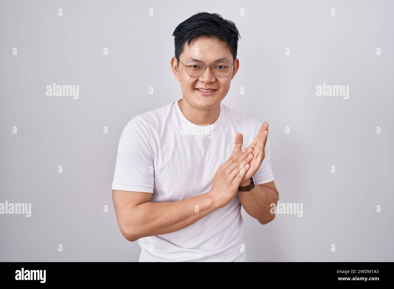 Young asian man standing over white background clapping and applauding ...