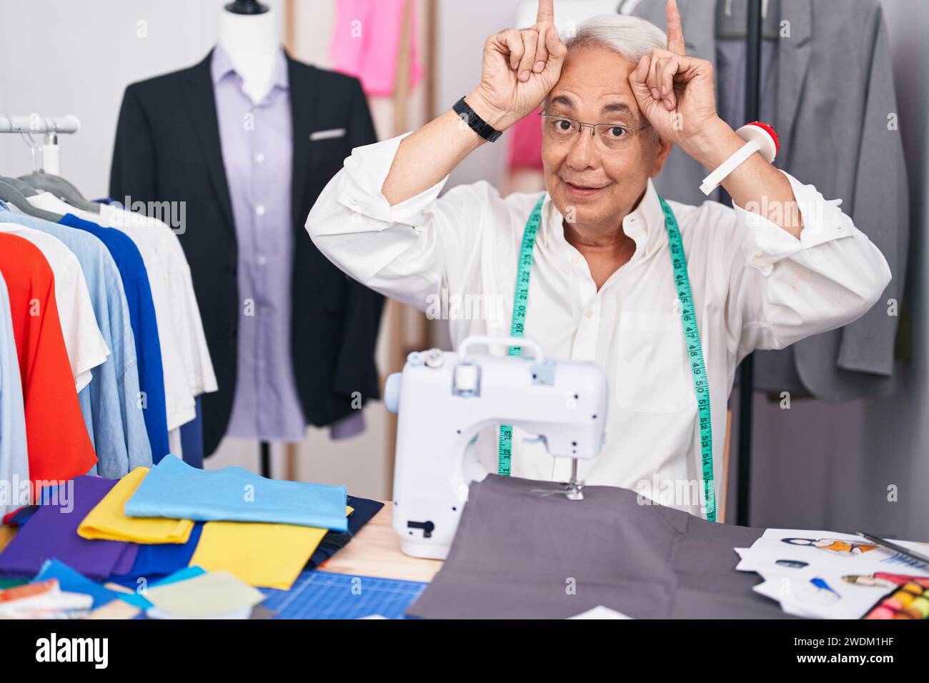 Middle age man with grey hair dressmaker using sewing machine doing ...