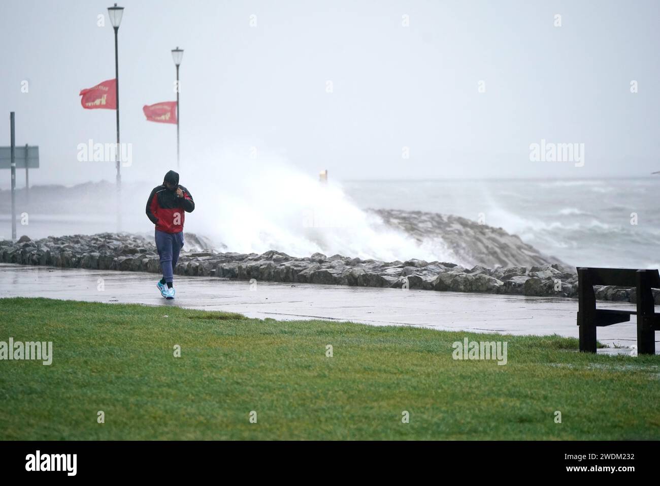 A person looking walking past high waves in Salthill, Galway, during ...
