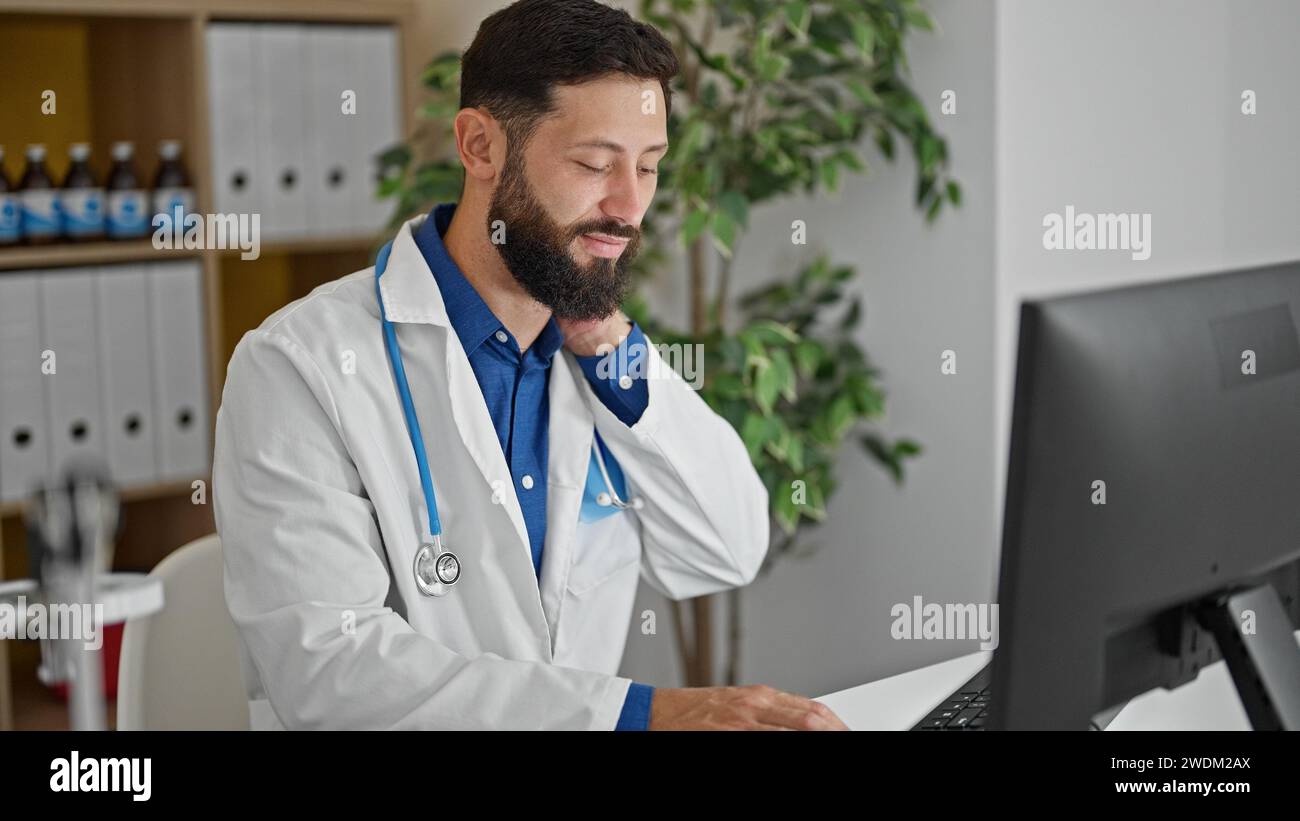 Young hispanic man doctor using computer stressed suffering cervical ...