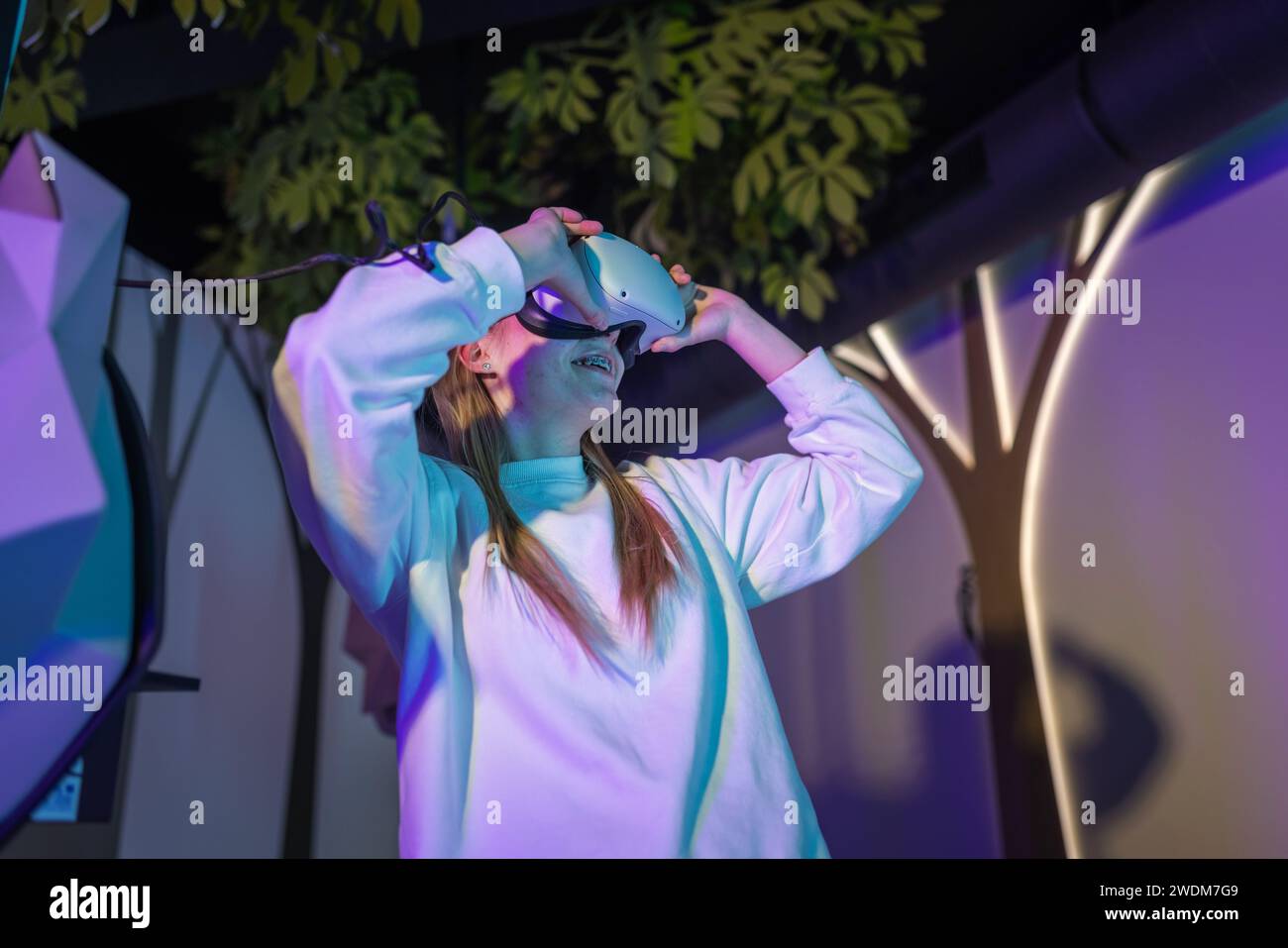 Teenage girl having fun in a natural history museum VR room, wearing ...