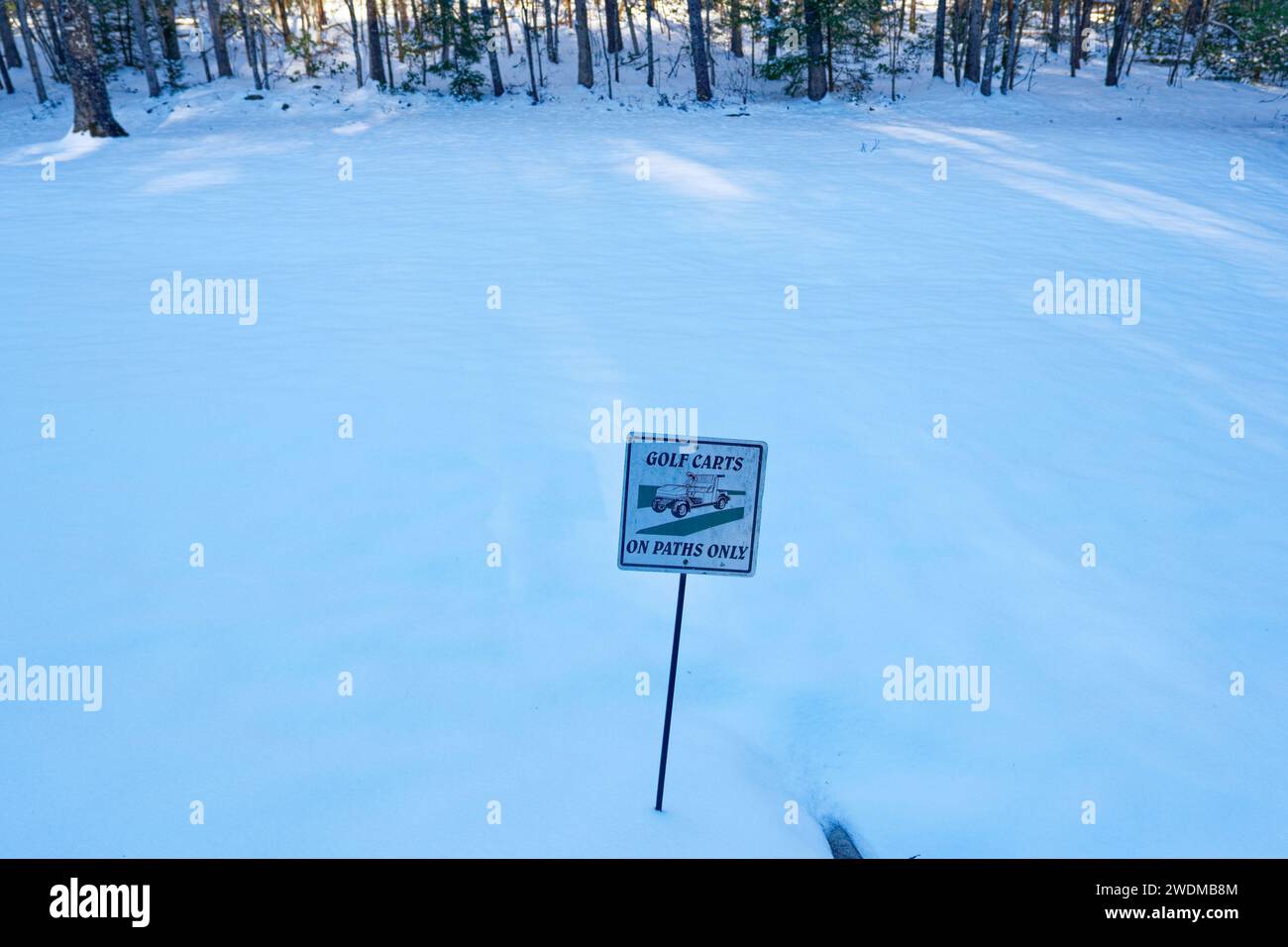 Golf carts on paths only signage alongside the path in a snow covered ...