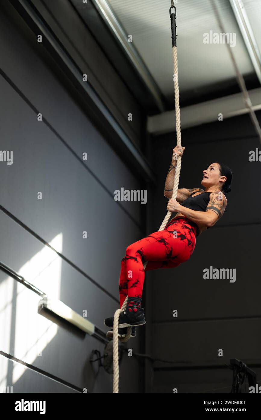 Strong woman climbing rope in a cross training gym Stock Photo - Alamy
