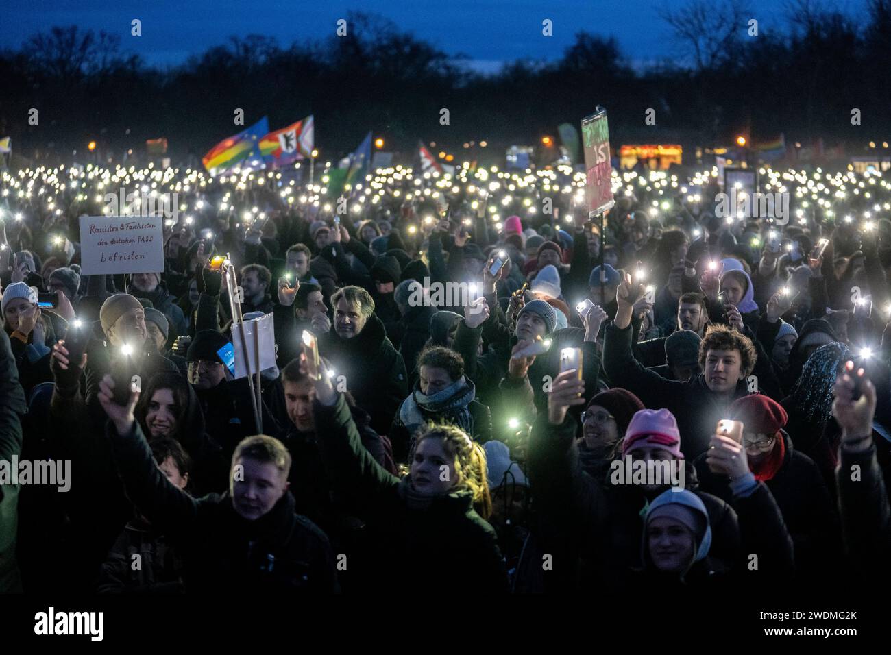 People hold up their cell phones as they protest against the AfD party ...