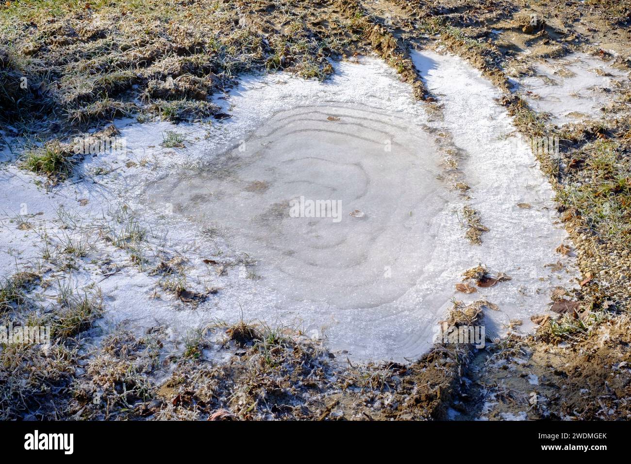 intricate swirls form patterns in large frozen puddle rural countryside ...