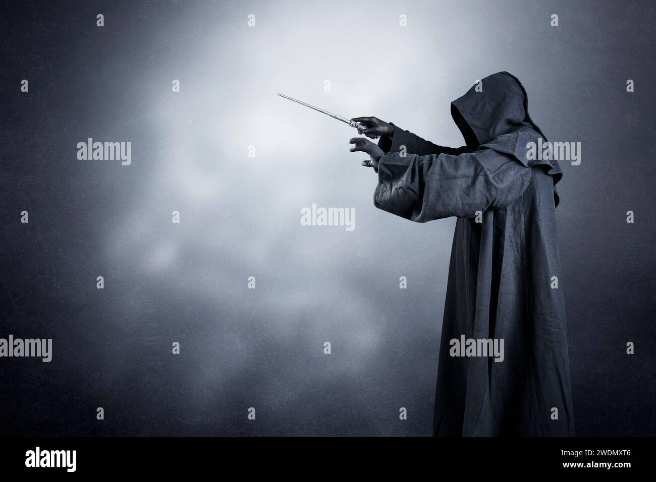 Wizard with hooded cape and magic wand over dark misty background Stock ...
