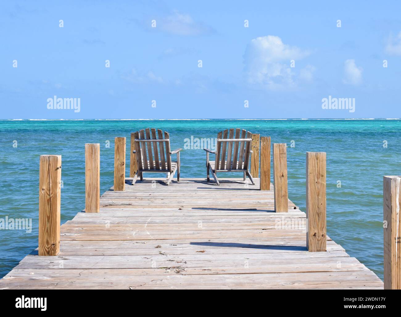 A pier with two chairs facing the Caribbean Sea on a clear, sunny day ...