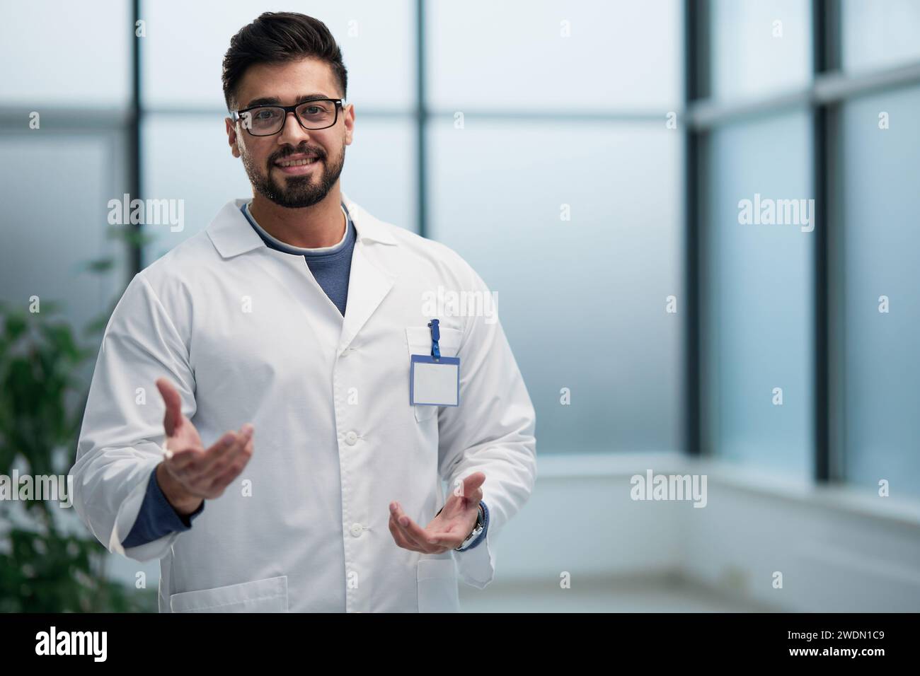 The doctor, an average man, makes a hand gesture inviting patients ...