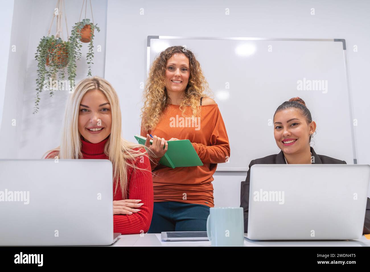 Three professional women confidently smile during a collaborative ...