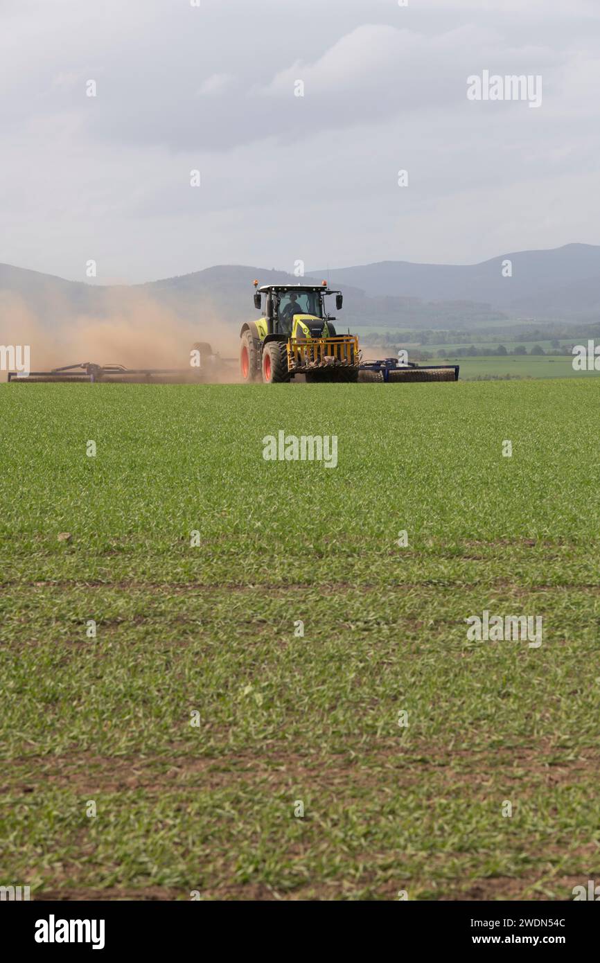 A View Across a Field of Spring Barley Towards a Claas Tractor Towing ...