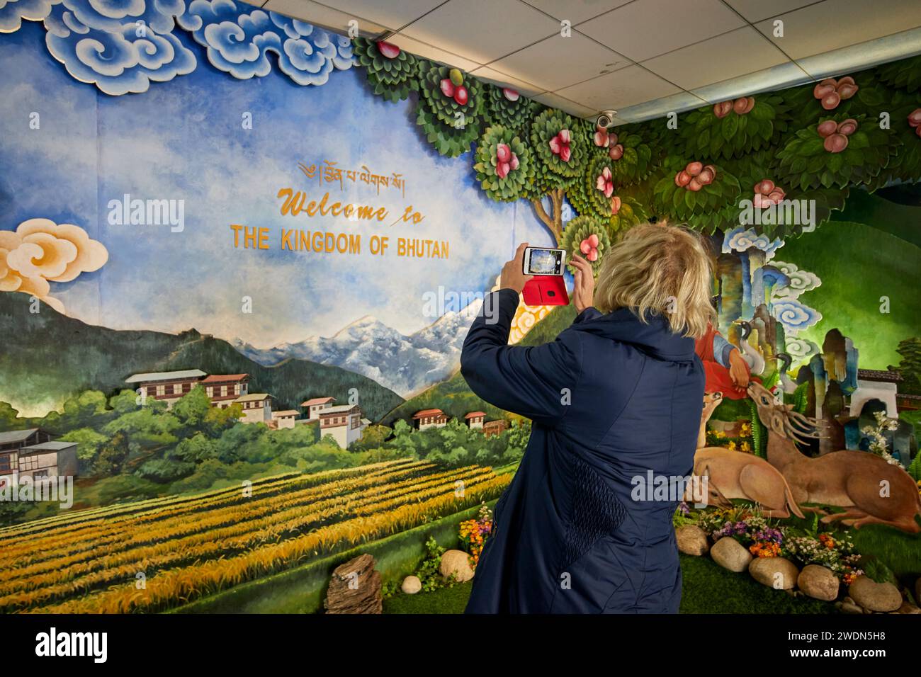 Tourist taking a photo of paintings of rural scenes at a Welcome to the ...