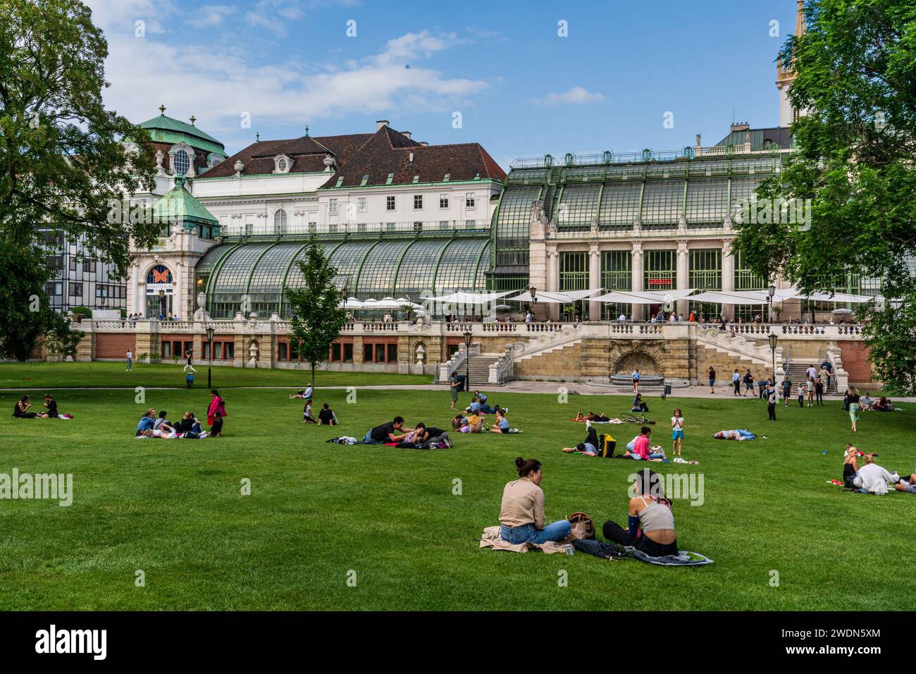 Vienna, AT – June 9, 2023 Visitors relaxing in the Burggarten, a statue ...