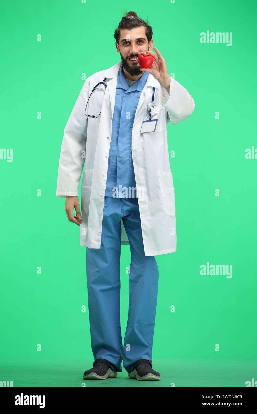 Male doctor, full-length, on a green background, shows a heart Stock ...