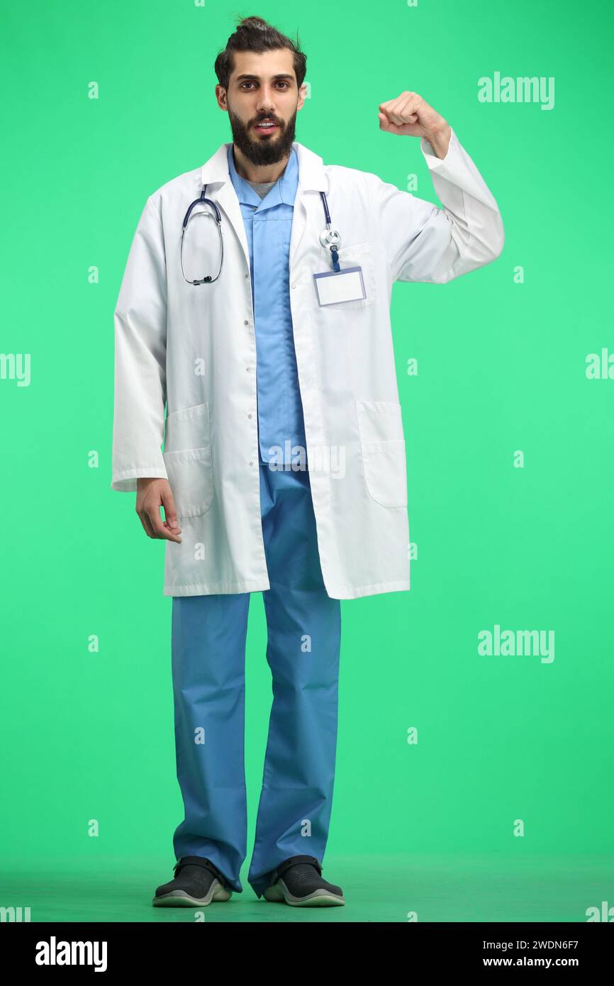 Male doctor, full-length, on a green background, shows strength Stock ...