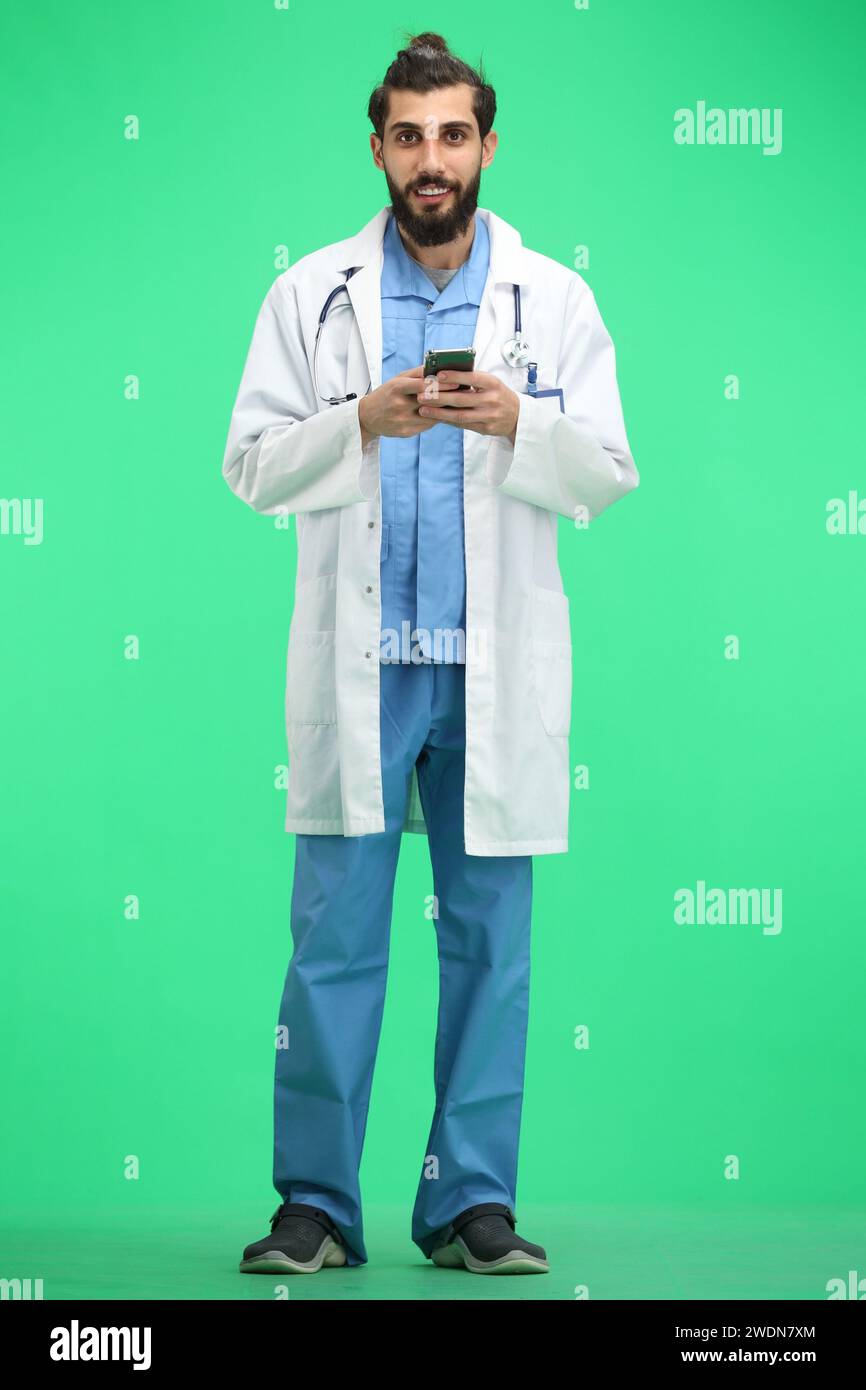 Male doctor, full-length, on a green background, with a phone Stock ...