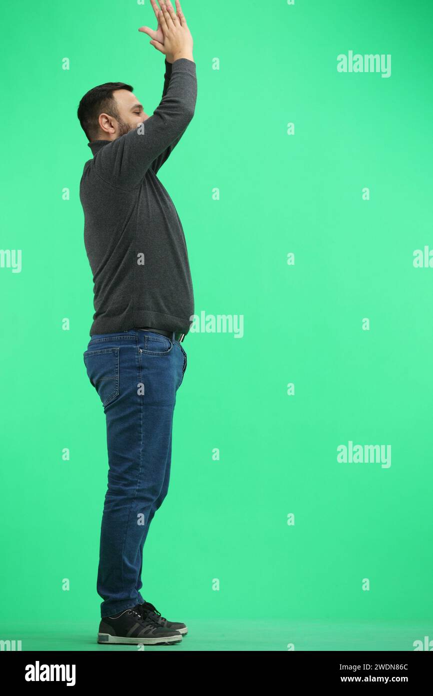 A man, full-length, on a green background, claps Stock Photo - Alamy