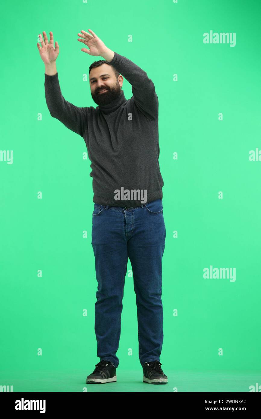 A man, full-length, on a green background, waving his arms Stock Photo ...