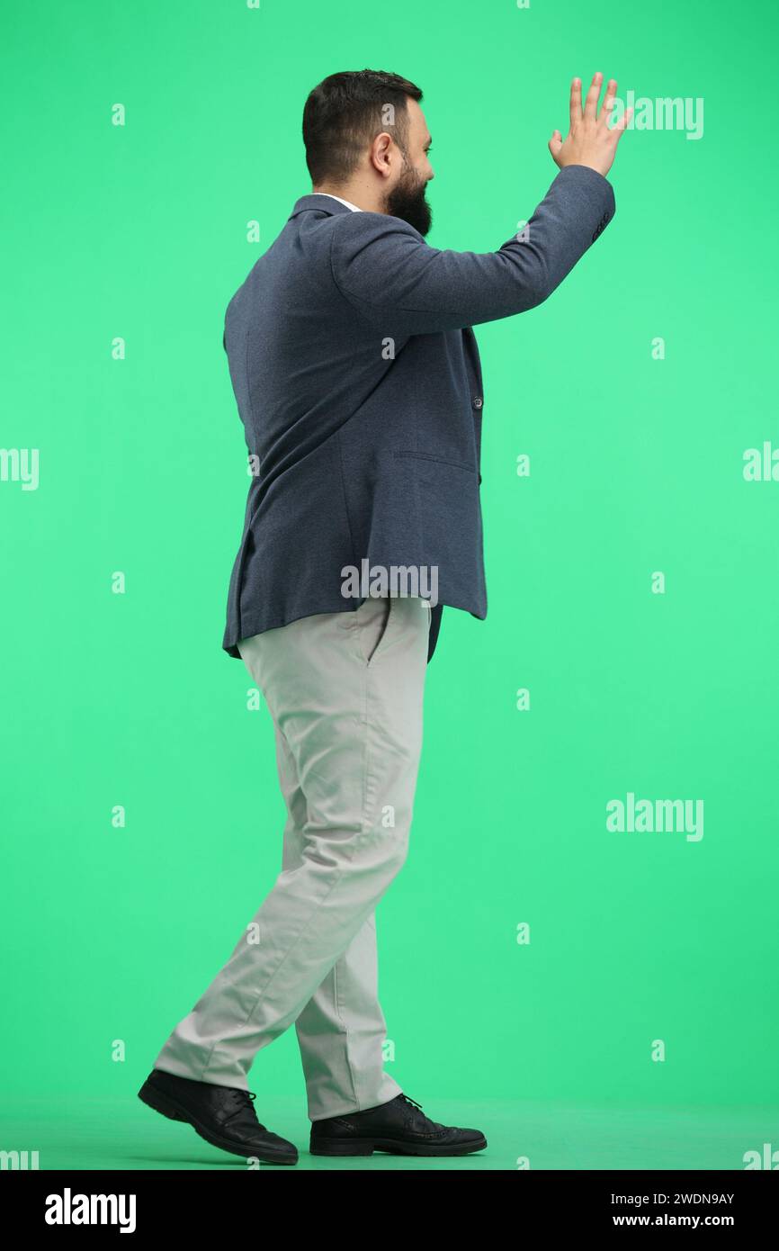 A man, full-length, on a green background, waving his hand Stock Photo ...