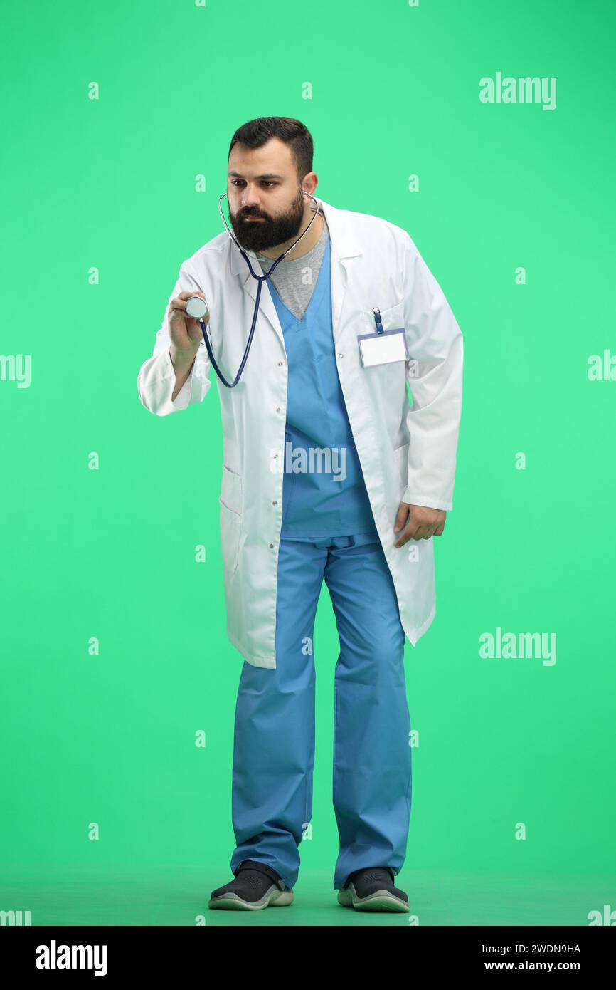 Male doctor, full-length, on a green background, with a stethoscope ...