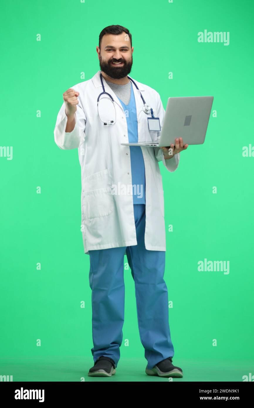 Male doctor, full-length, on a green background, with a laptop Stock ...