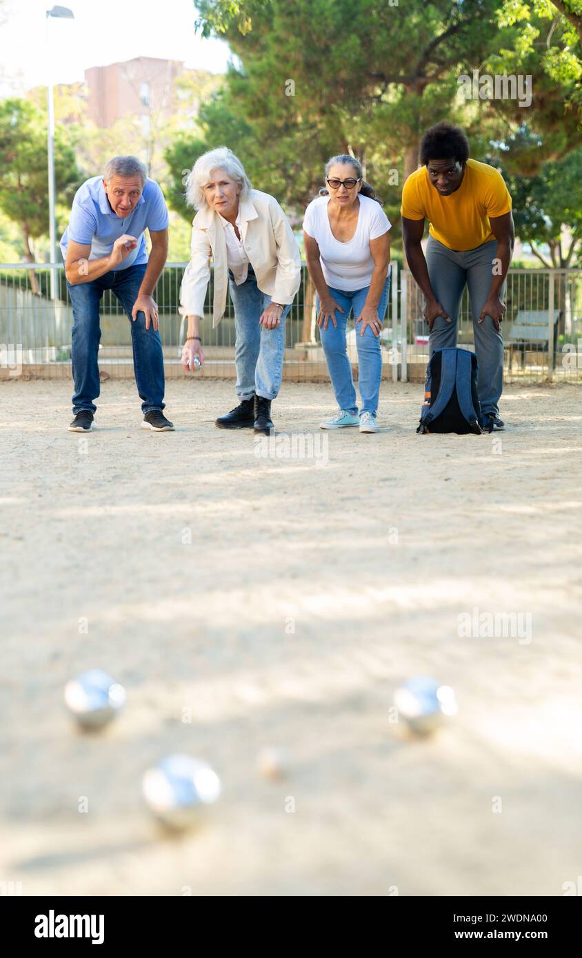 A group of multiracial mature adult people playing patanque game ...