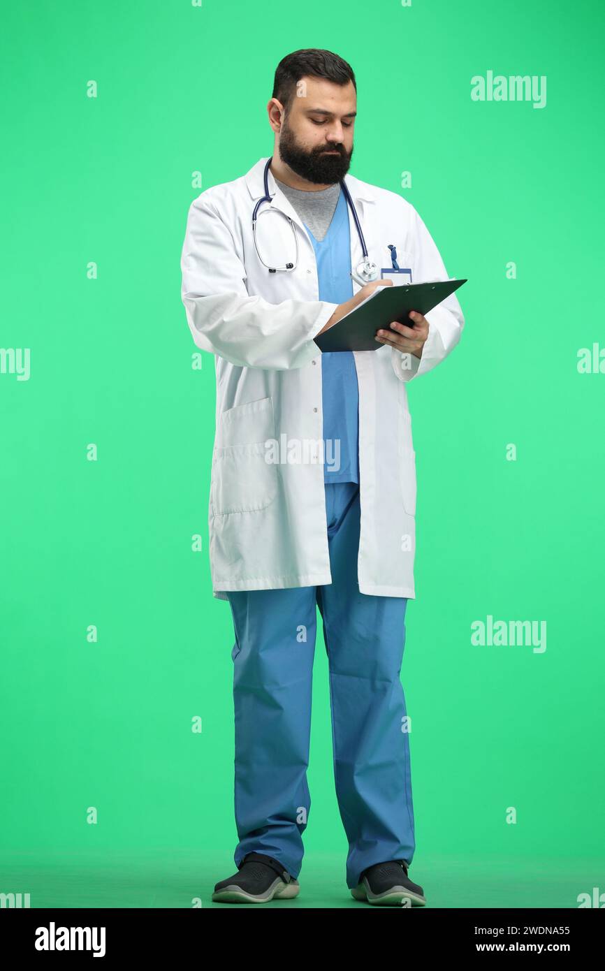 A male doctor, full-length, on a green background, writes Stock Photo ...