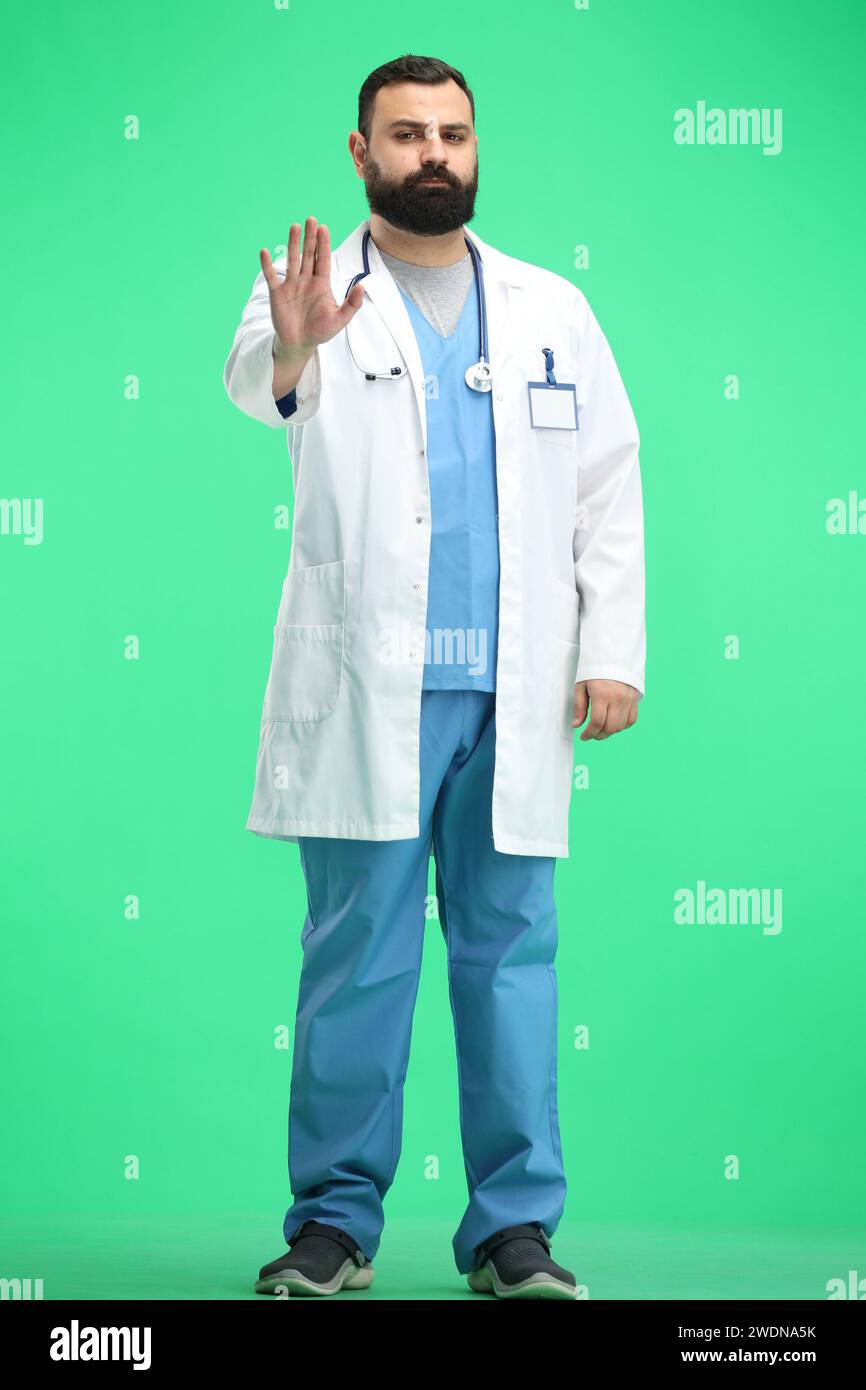 Male doctor, full-length, on a green background, shows a stop sign ...