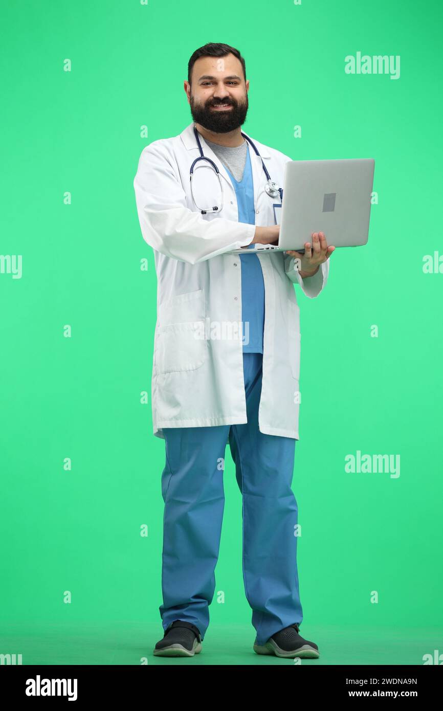 Male doctor, full-length, on a green background, with a laptop Stock ...