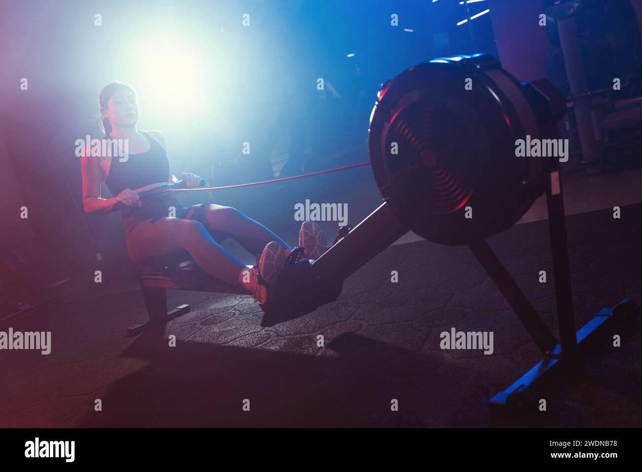 In the gym, a woman trains on a rowing machine, surrounded by a ...