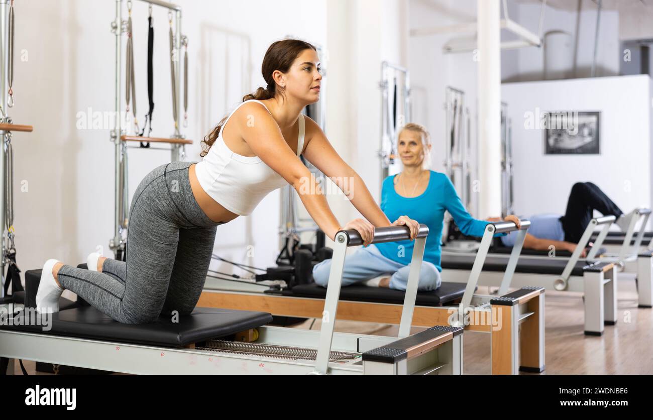 Positive young female doing Pilates exercises for back while using ...