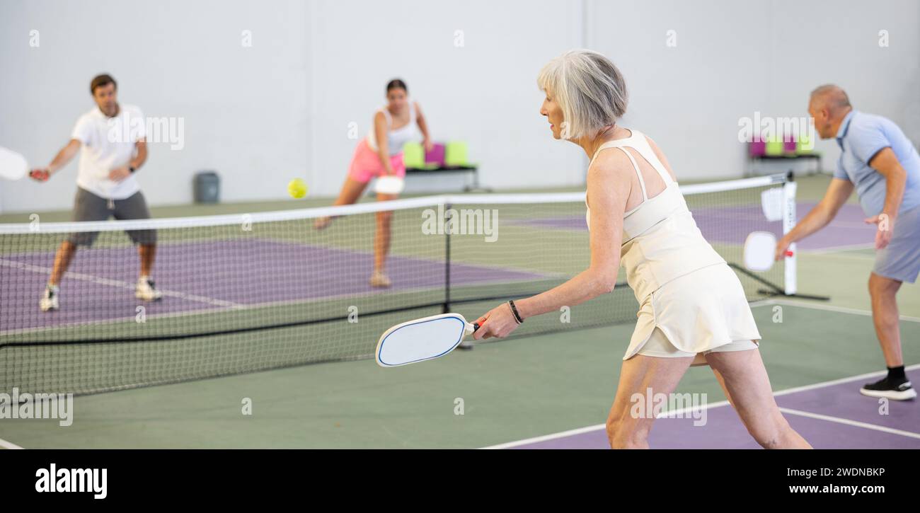Rear view of aged woman playing pickleball on indoor court Stock Photo ...