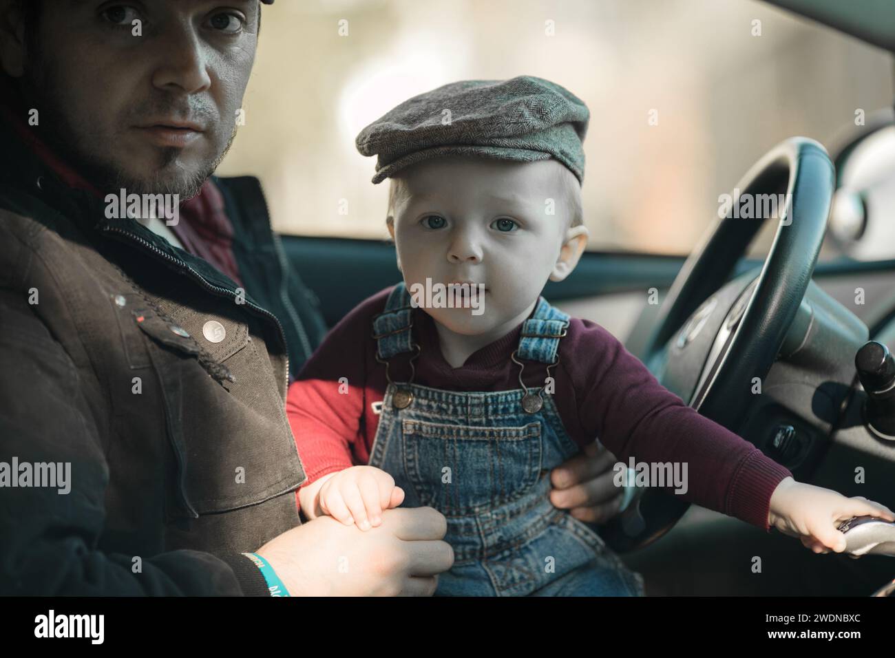 Young father with his little son driving car together. Child sit on dad ...