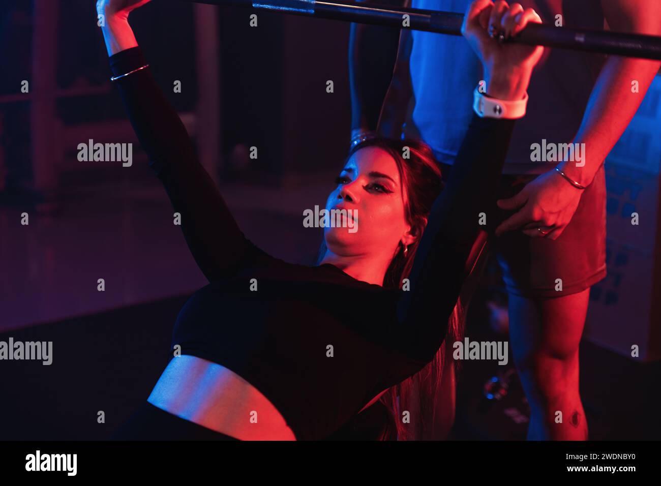 A dedicated female athlete engages in an incline bench press, guided by ...