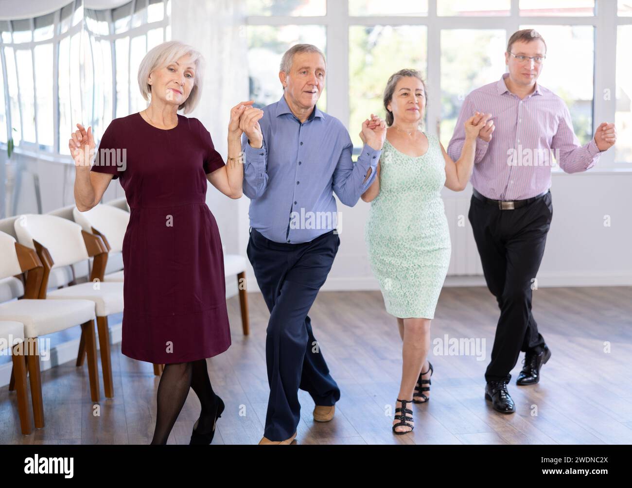 Group of elderly people with middle-aged man perform Irish folk dance ...