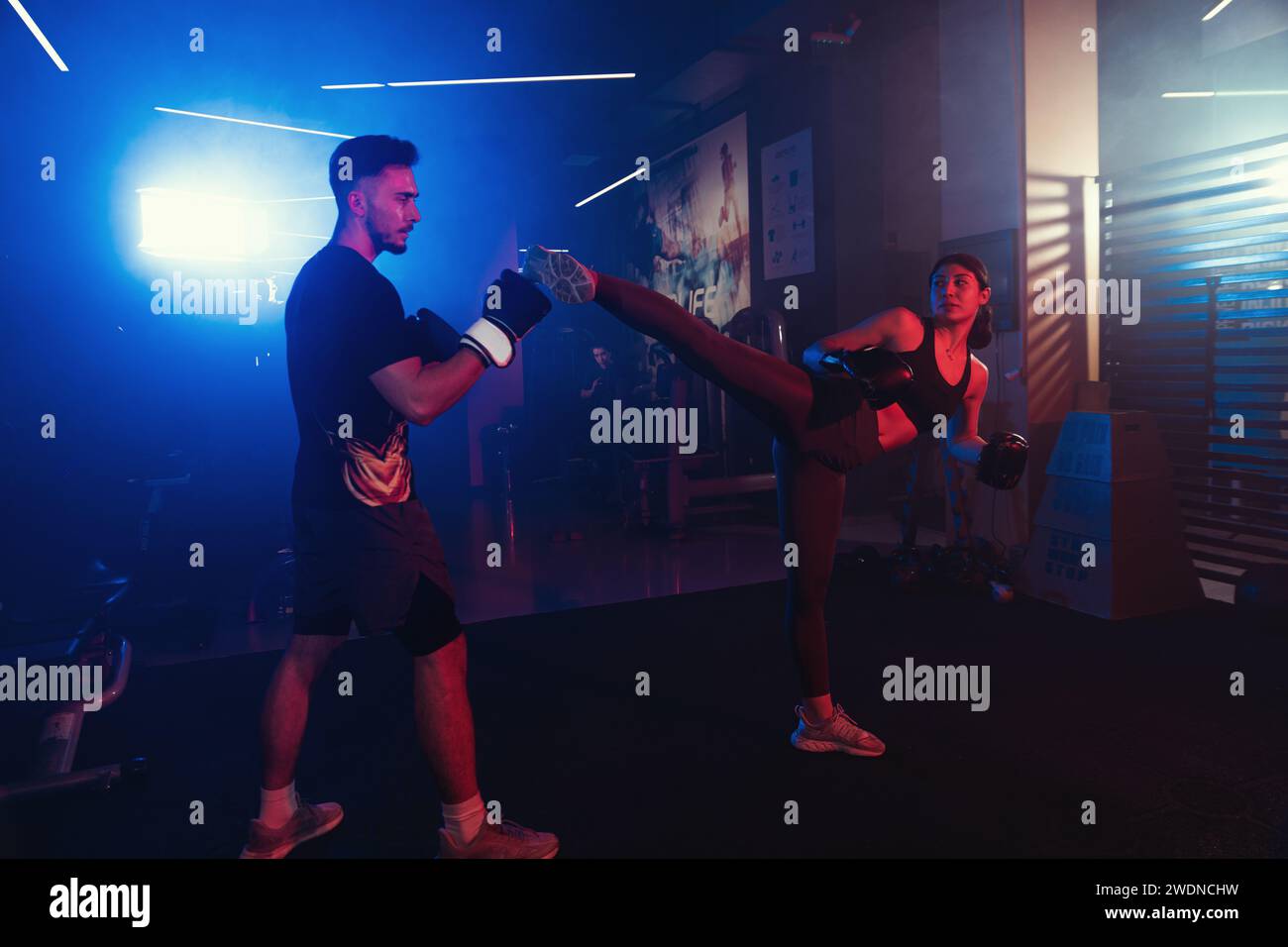 A woman executes a high kick as her partner defends in a gym session ...